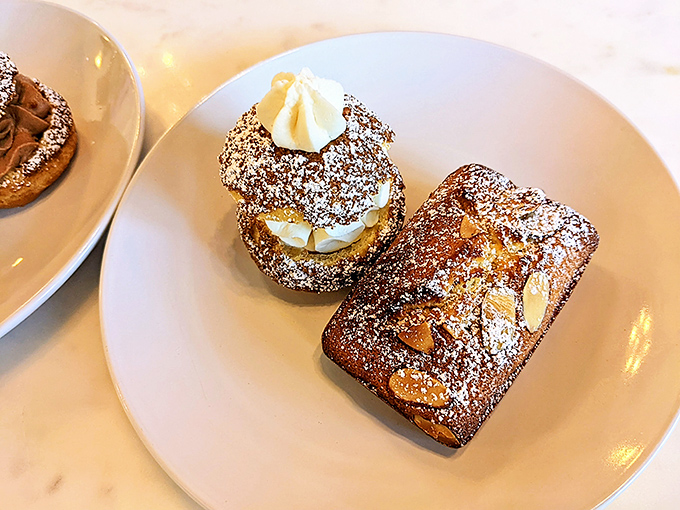 Two French classics sharing a plate like old friends. The cream-filled pastry and almond-studded financier aren't competing—they're complementing.