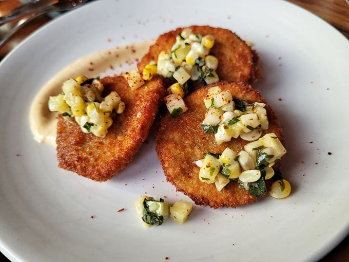 Crispy fried green tomatoes topped with sweet corn relish &ndash; Southern comfort meets Vermont freshness in perfect harmony.