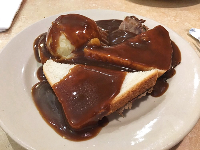 Hot roast beef sandwich swimming in gravy &ndash; comfort food that wraps around you like your grandmother's favorite quilt on a cold day.