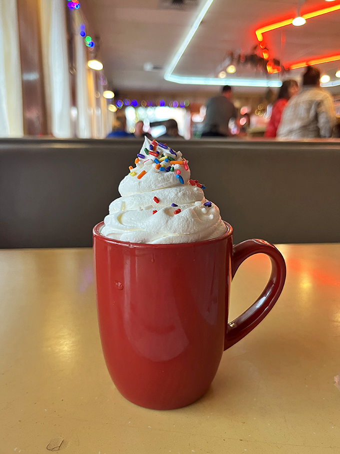 Hot chocolate that doesn't know when to quit, topped with a cloud of whipped cream and colorful sprinkles.