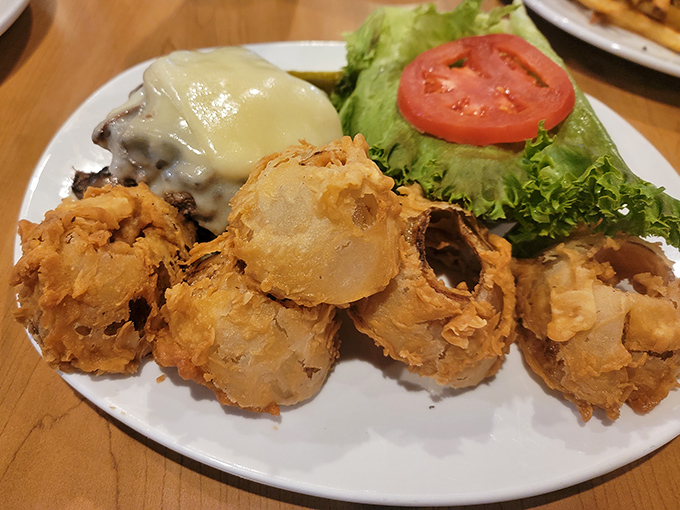 Onion rings that could double as edible jewelry, paired with a burger that demands two-handed commitment. This plate doesn't just satisfy hunger&mdash;it conquers it.