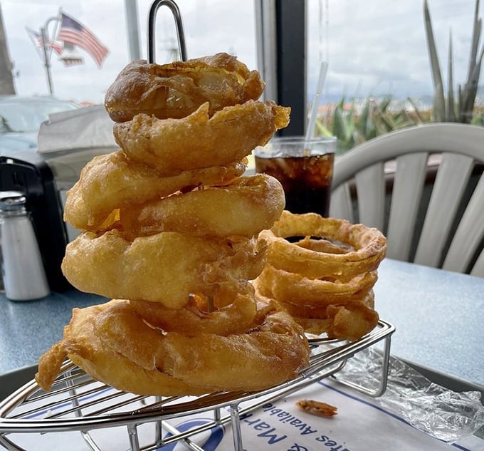 Onion rings stacked like golden Olympic rings. Crispy, light, and defying gravity in a tower of fried perfection that demands to be photographed.
