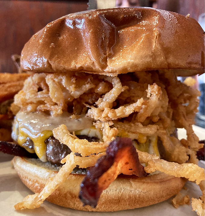 This burger gets topped with crispy onion strings and sauce, creating a situation that napkins alone cannot handle properly.
