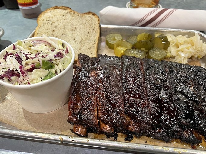 These ribs wear their bark like a badge of honor, that perfect crust protecting meat so tender it practically surrenders at the sight of your fork.