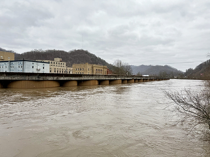 The Tug Fork River swells with rainwater and purpose, a liquid boundary between states that locals cross with barely a second thought.