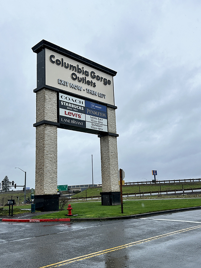 The towering sign stands like a retail lighthouse, guiding deal-seekers safely to shore. Those brand names promise fashion salvation just off the highway.