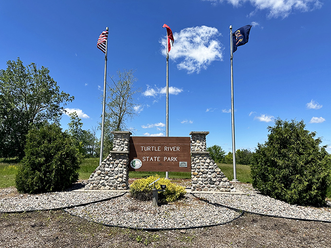 The entrance sign stands proud beneath three flags, like a low-key bouncer who doesn't need to check your ID but still commands respect.