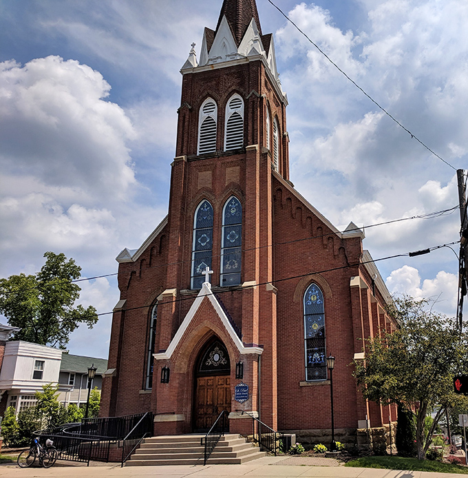 This brick church reaches skyward with its impressive spire, stained glass windows catching light like jewels in Athens' architectural crown.