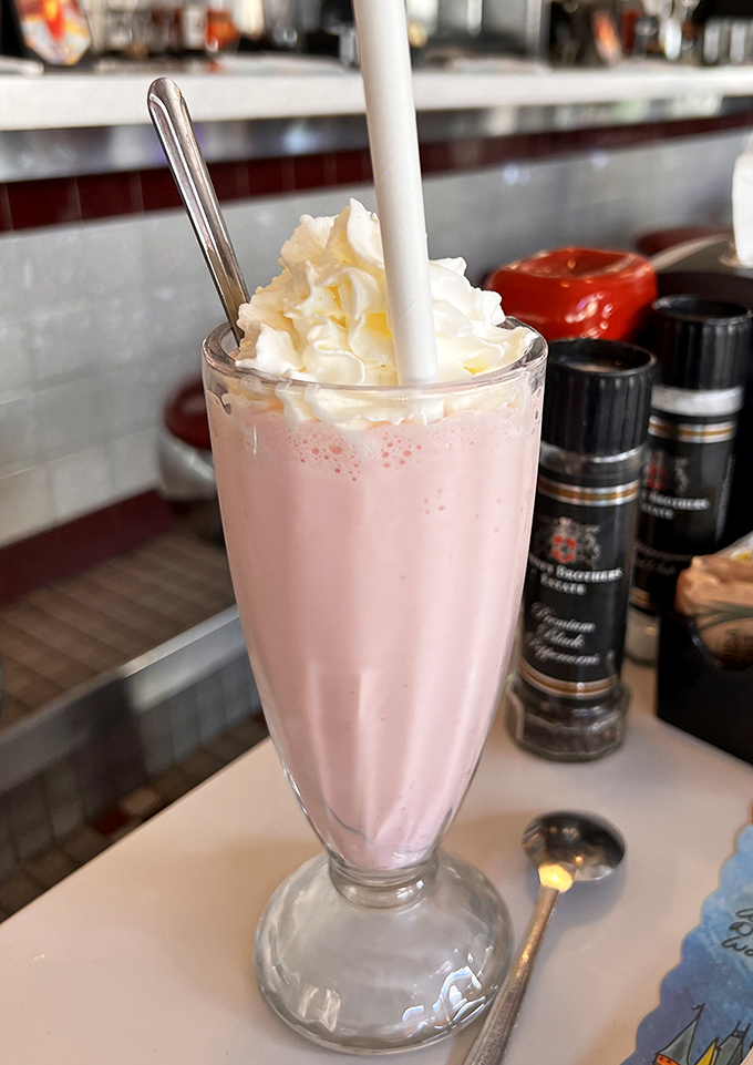 That strawberry milkshake is thick enough to require upper body strength, topped with whipped cream that refuses to quit.
