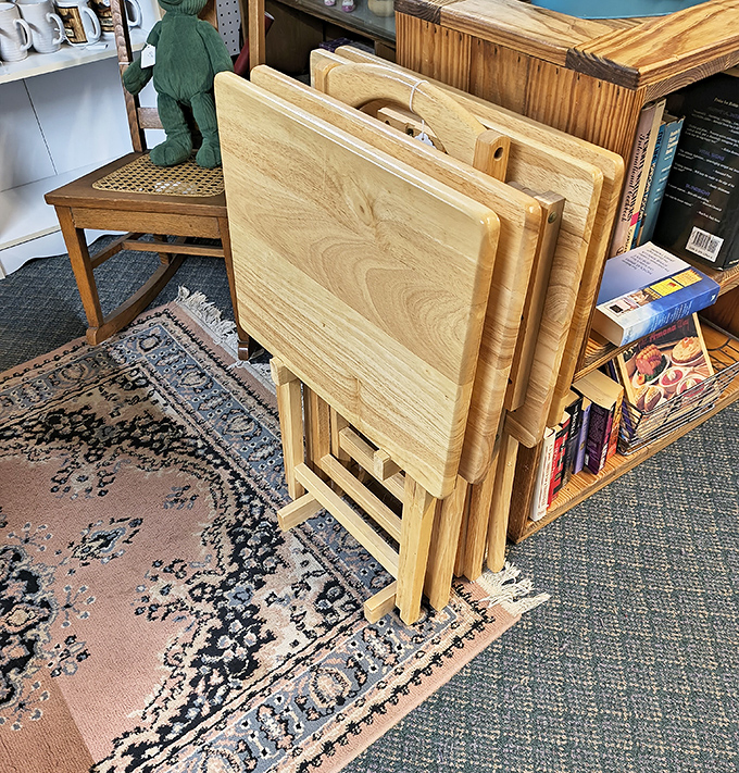 A small set of wooden TV tray tables sits neatly folded together in a corner of the room.