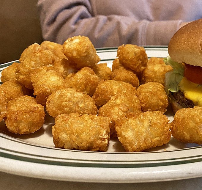Tater tots with the perfect crisp-to-soft ratio, clustered like golden nuggets next to a cheeseburger that means business.
