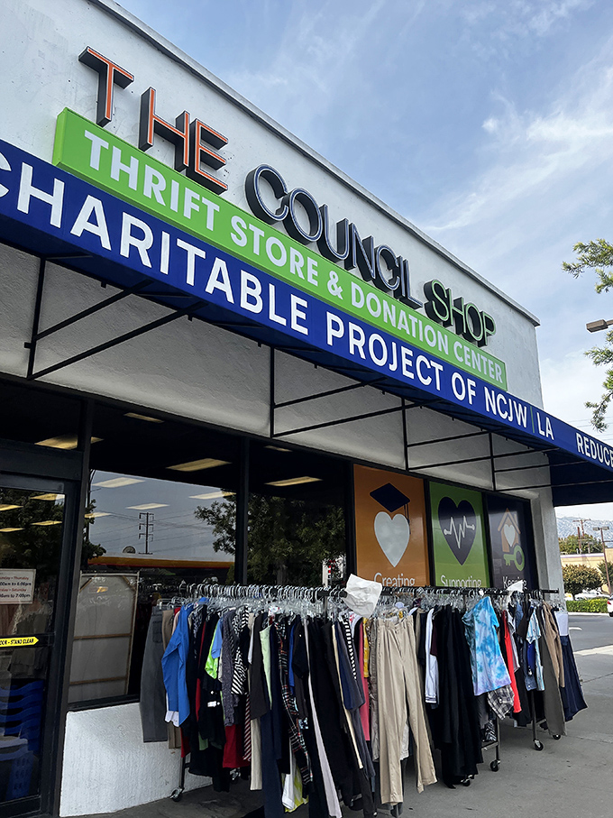 Clothing racks flank the entrance like welcoming committees of fabric. The "CHARITABLE PROJECT OF NCJW LA" sign hints at treasures freshly arranged inside.