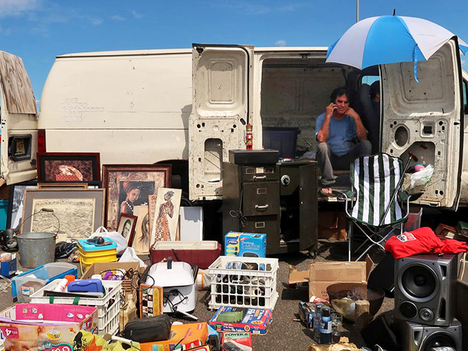 The vendor takes a call while surrounded by the physical remnants of other people's memories. One man's storage problem becomes another's decorating solution.