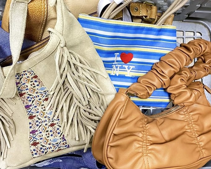 A fringe-adorned bohemian bag nestles against its leather cousins. These purses have stories to tell—if only they could talk about their previous adventures.