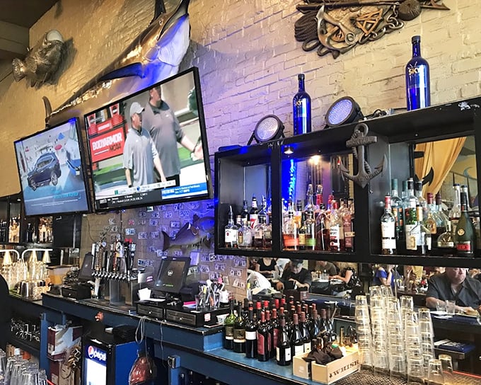 The bar gleams with bottles like a lighthouse of libations. Fish mounts on the wall remind you where your next course originated.