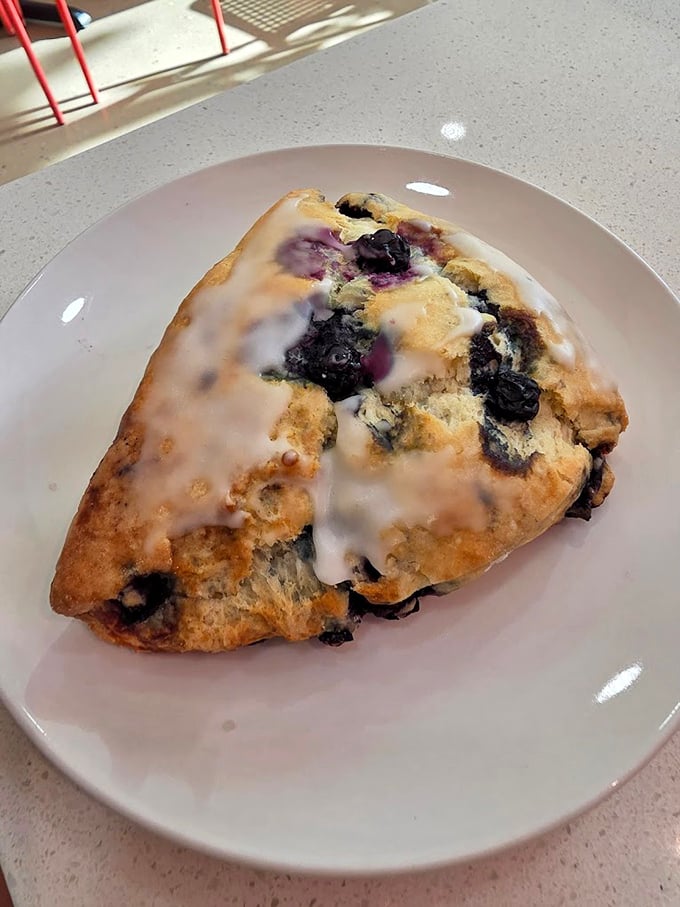 This blueberry scone looks like it's been caught mid-explosion, berries bursting through buttery dough like delicious little flavor bombs.