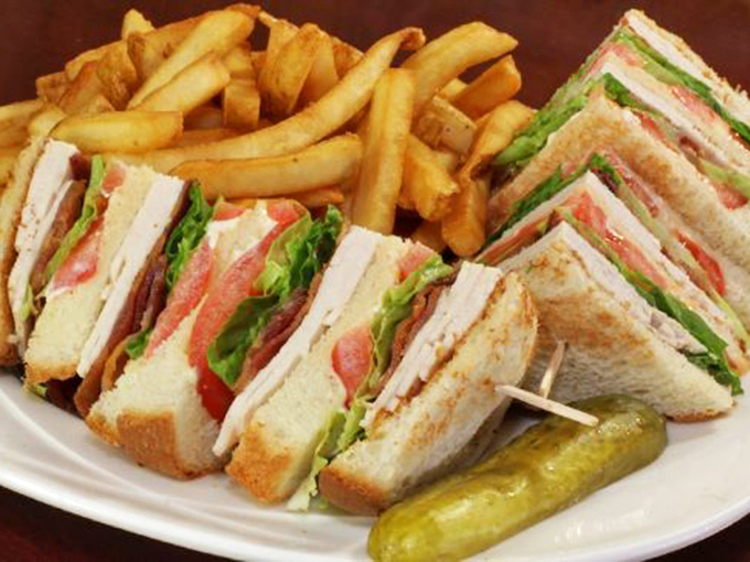 The club sandwich&mdash;three stories of deliciousness that makes skyscrapers jealous, with a pickle keeping guard.
