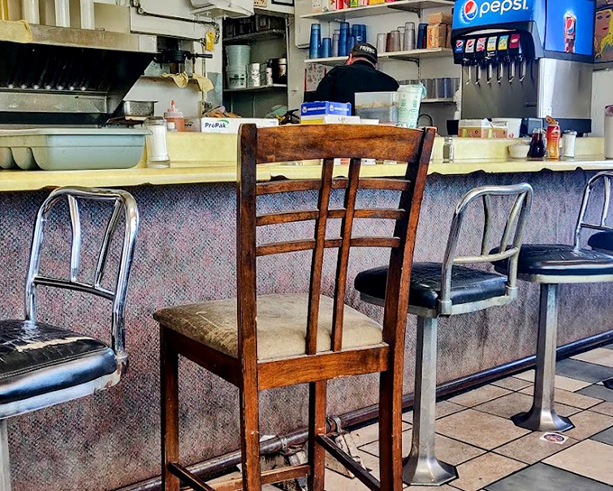 The worn wooden chair against the counter tells stories of countless regulars who've made this their second kitchen, returning for that perfect cup of diner coffee.