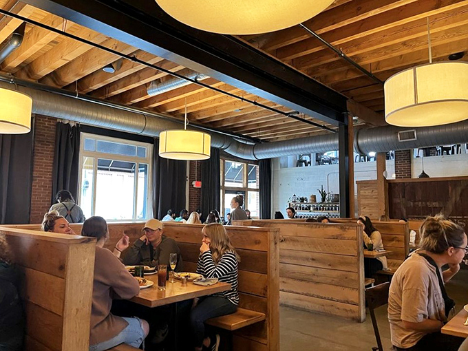 Diners lost in conversation and culinary bliss, surrounded by wooden booths that create intimate spaces within the larger communal experience.