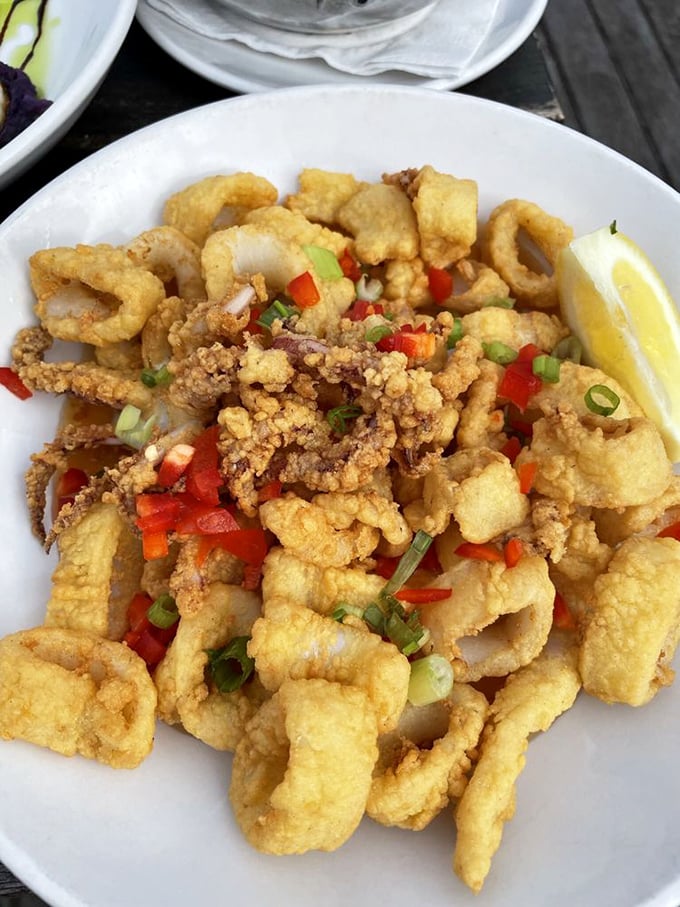 Fried calamari that crackles with each bite, adorned with colorful peppers like confetti at a seafood celebration.