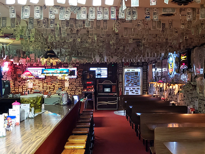 The ceiling and walls disappear beneath thousands of dollar bills, creating a green canopy that's part decor, part customer hall of fame.