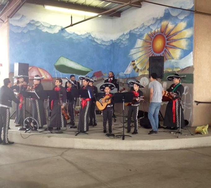 A mariachi band performs against a vibrant mural backdrop, adding soundtrack and soul to your shopping adventure.