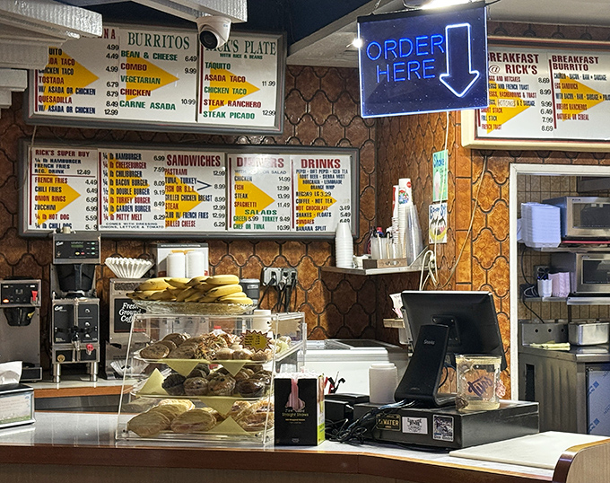The order counter&mdash;where dreams become reality. That neon "ORDER HERE" sign might as well say "HAPPINESS DISPENSED WHILE YOU WAIT."