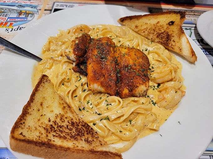 Blackened fish over creamy pasta&mdash;where comfort food meets coastal cuisine. Those two pieces of toast aren't decoration; they're essential sauce-sopping tools.