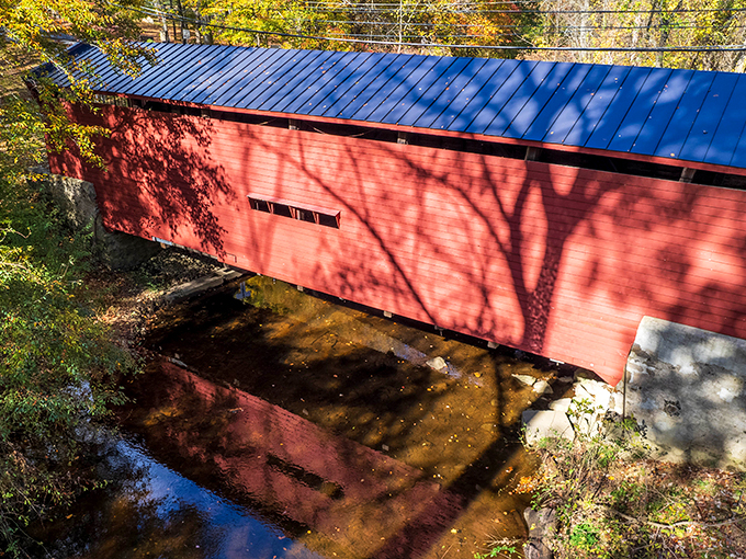 From above, the bridge's blue roof contrasts beautifully with its red sides and the golden-brown creek below&mdash;a three-layer visual feast.