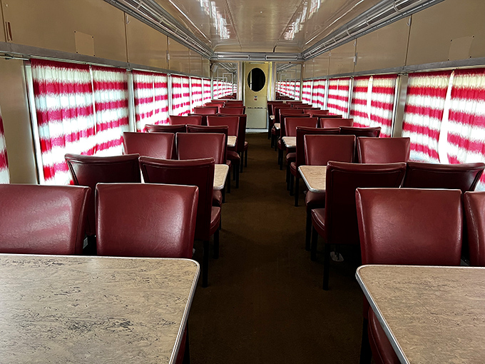 These vintage dining car seats have witnessed countless conversations and landscapes, their rich burgundy upholstery inviting modern visitors to imagine bygone journeys.