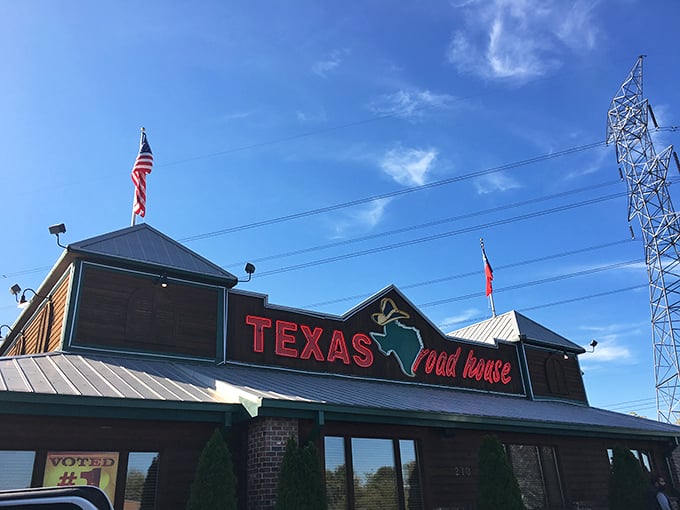 The red neon glow of Texas Roadhouse&mdash;where chain restaurant reliability meets surprisingly serious steak credentials.
