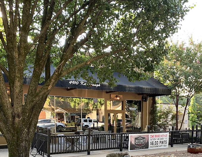 Sunlight catches The Pizzeria's patio fence, creating shadows that dance like the flavors waiting on your perfect pie inside.
