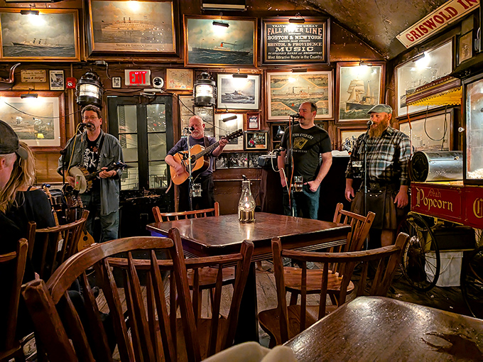 Sea shanties and folk tunes fill the air as musicians perform against a backdrop of maritime paintings, creating the soundtrack for an authentic New England evening.