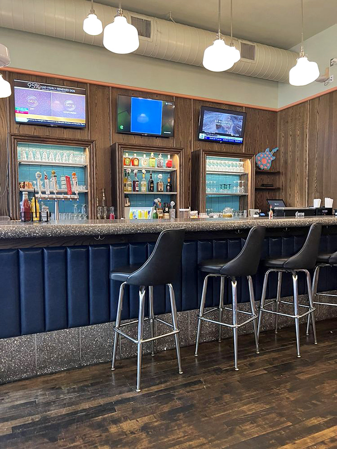 The bar area blends vintage charm with modern comfort, where classic cocktails are poured beneath the glow of multiple TV screens.