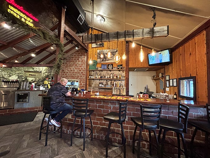 The bar area blends rustic charm with modern comfort&mdash;exposed brick, pendant lighting, and that magnificent rock wall watching over everything.