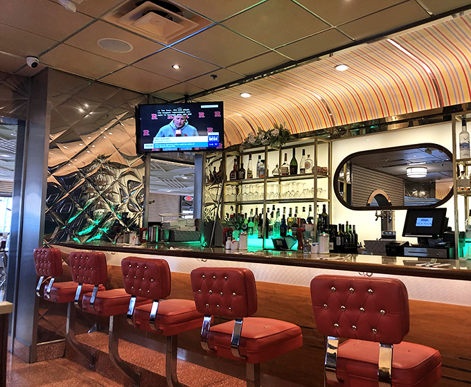 The bar area beckons with its crimson stools and glowing bottles, promising liquid courage and the perfect perch for observing diner society in its natural habitat.