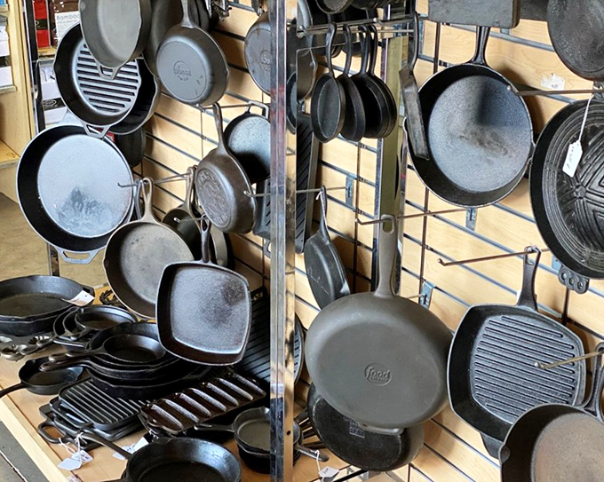 Cast iron heaven! These seasoned beauties hang like culinary trophies, each pan telling stories of countless meals and kitchen triumphs.