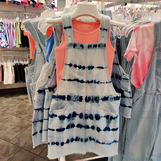 Tie-dye denim meets coral tops in a display that whispers, "Summer isn't over until the outlet sales say it is."