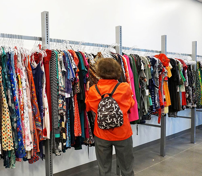 Color-coded clothing racks stretch toward the horizon, a textile rainbow where vintage patterns mingle with contemporary styles in democratic harmony.
