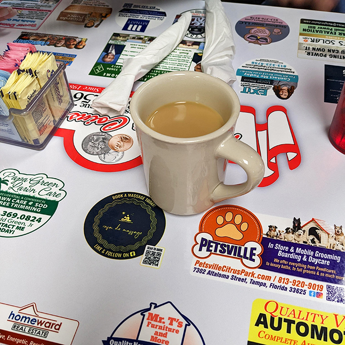 The coffee comes in those thick white mugs that somehow make everything taste better, served on placemats advertising local businesses since forever.