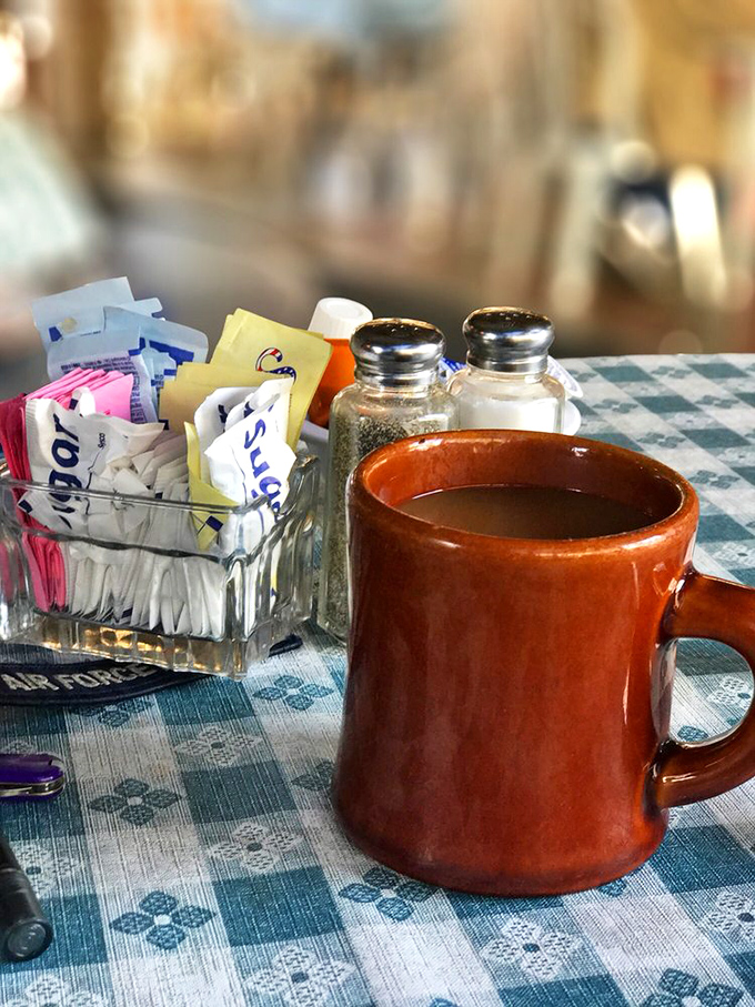 That brown ceramic mug isn't just holding coffee – it's cradling liquid motivation with a side of sugar packets standing by for reinforcement.