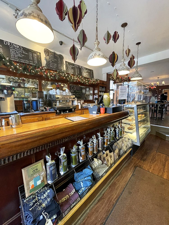 The coffee bar doubles as a stage where baristas perform their morning magic, beneath whimsical hanging decorations and warm pendant lights.