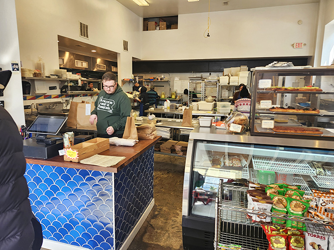 Behind the blue-tiled counter, sandwich artists work their magic with the precision of surgeons and creativity of painters.