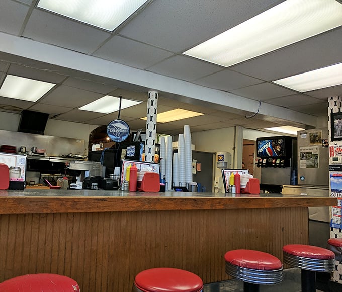 The counter where regulars have worn grooves in the seats, solving the world's problems one cup of coffee at a time.