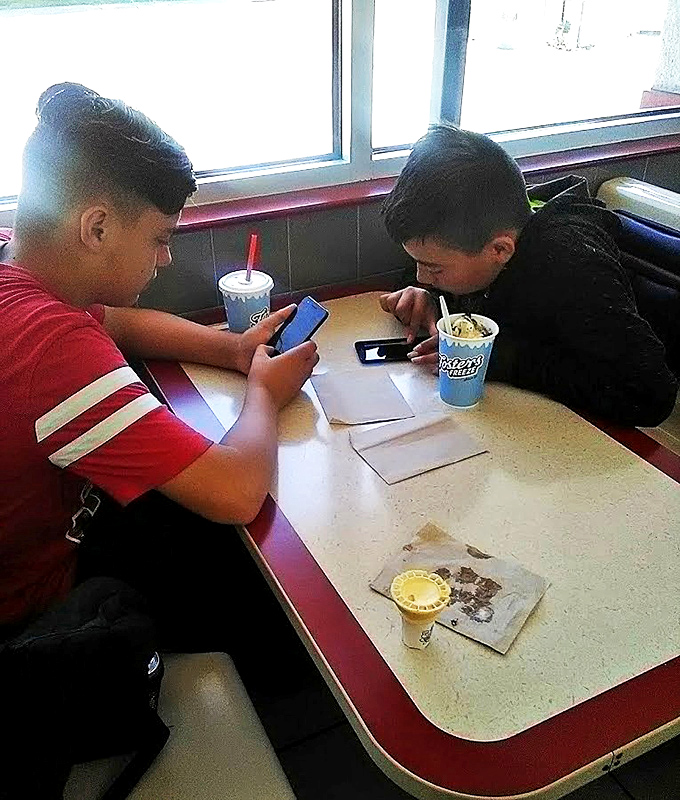 Two young diners absorbed in their phones, probably texting friends about the amazing treats they're enjoying at this classic spot.