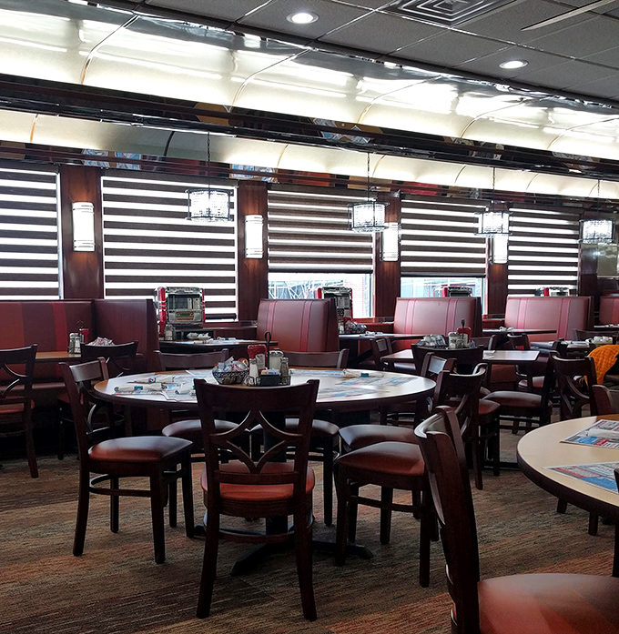 Red booths against striped window treatments create that distinctive diner atmosphere where important life decisions are made over bottomless coffee cups.