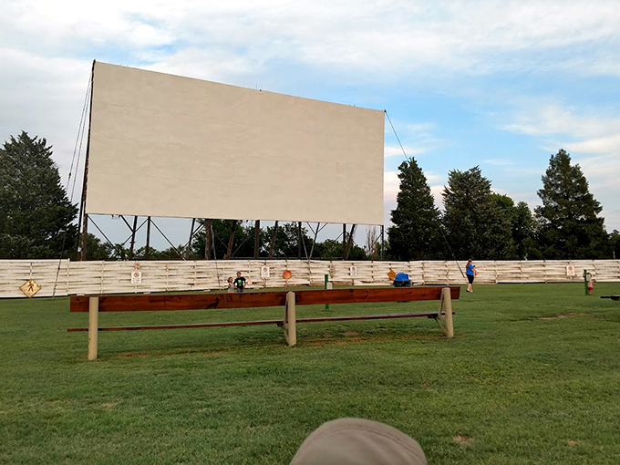 The massive screen awaits the evening's stories, a blank canvas against clouds that seem to understand they're part of the show.