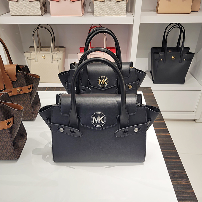 Michael Kors handbags standing at attention, like leather soldiers guarding the gateway to accessory heaven. Your budget trembles slightly.