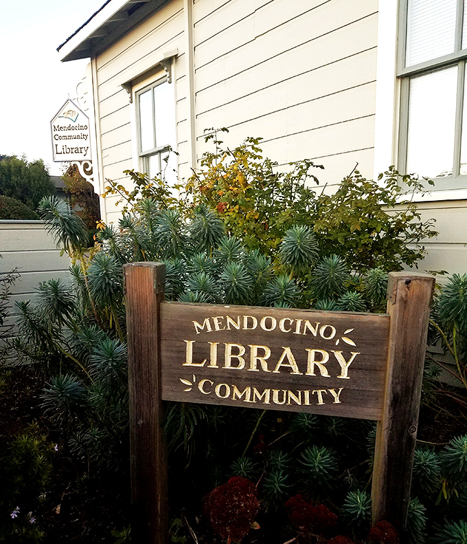 The Mendocino Library sign sits nestled among coastal plants, promising literary escapes that pair perfectly with foggy mornings.