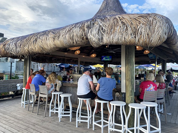 The tiki bar—where strangers become friends and vacation stories flow as freely as the frozen daiquiris under that perfect palm-thatched roof.